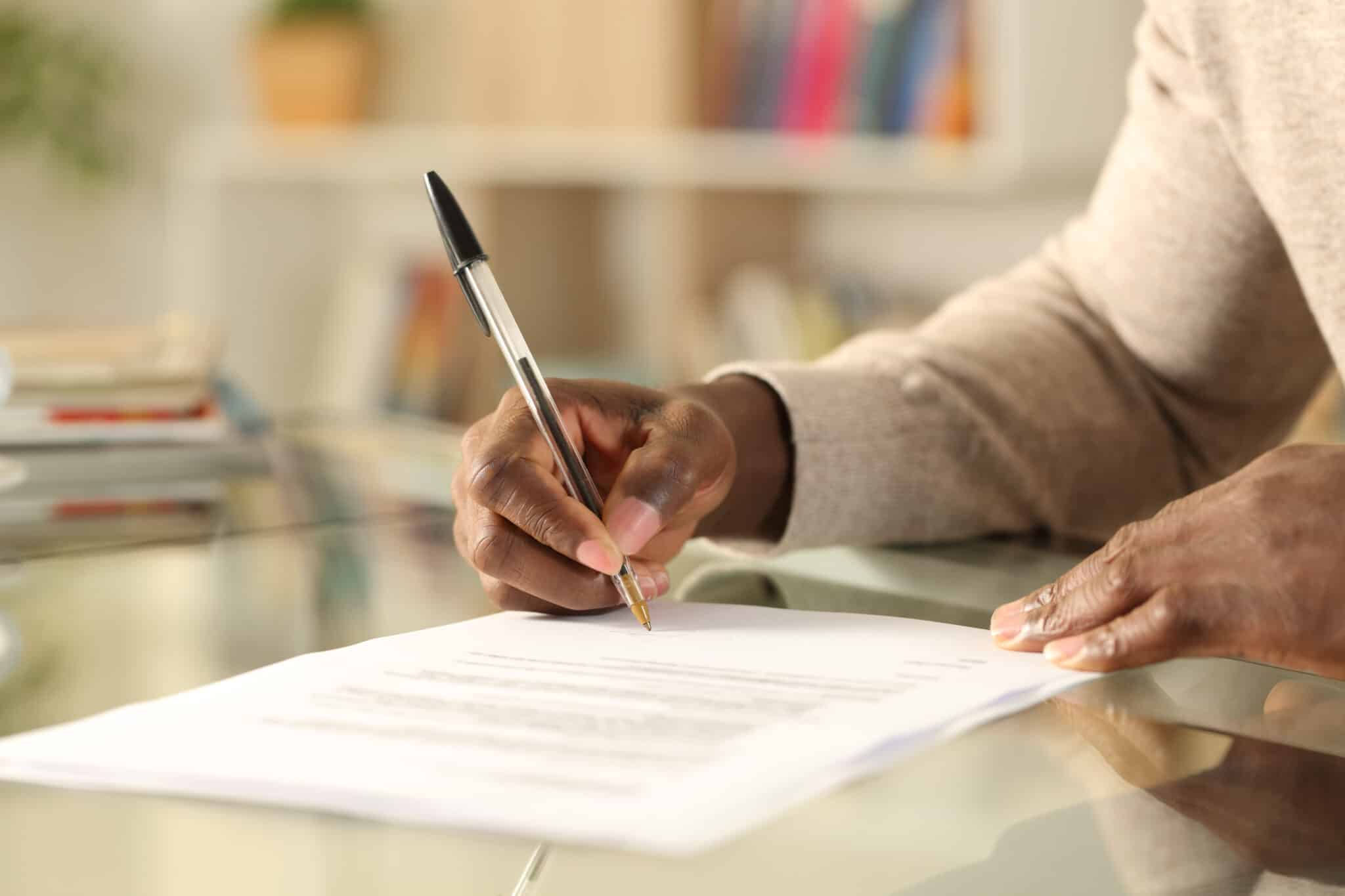 Close,Up,Of,Black,Man,Hands,Signing,Document,On,A - Séraphin-Marion